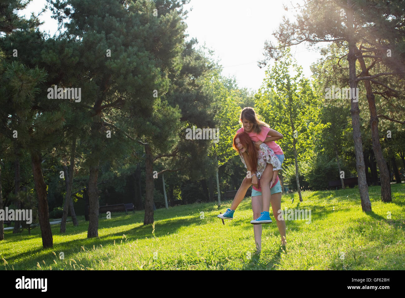 Young woman giving piggyback ride to friend Stock Photo - Alamy
