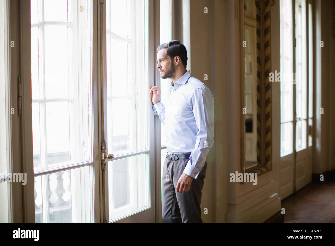 Young man looking through window Stock Photo - Alamy