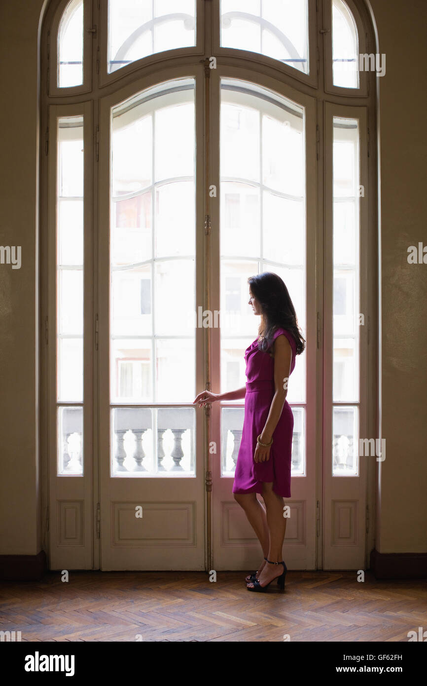 Young woman looking through window Stock Photo - Alamy