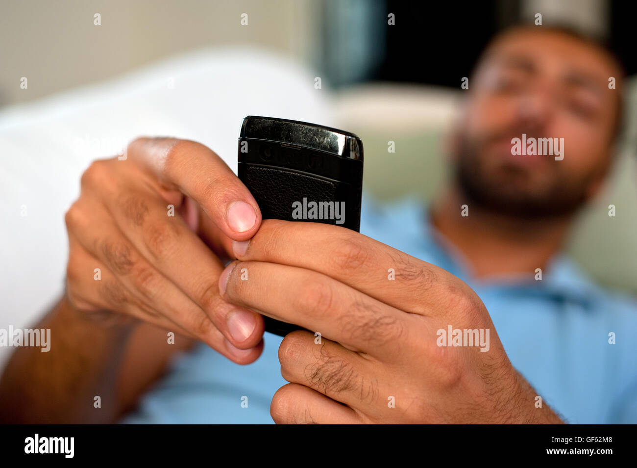 An Arab man uses his phone while lying on a sofa Stock Photo - Alamy