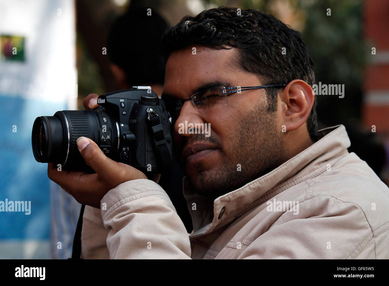 Bespectacled young man using a DSLR camera Stock Photo - Alamy