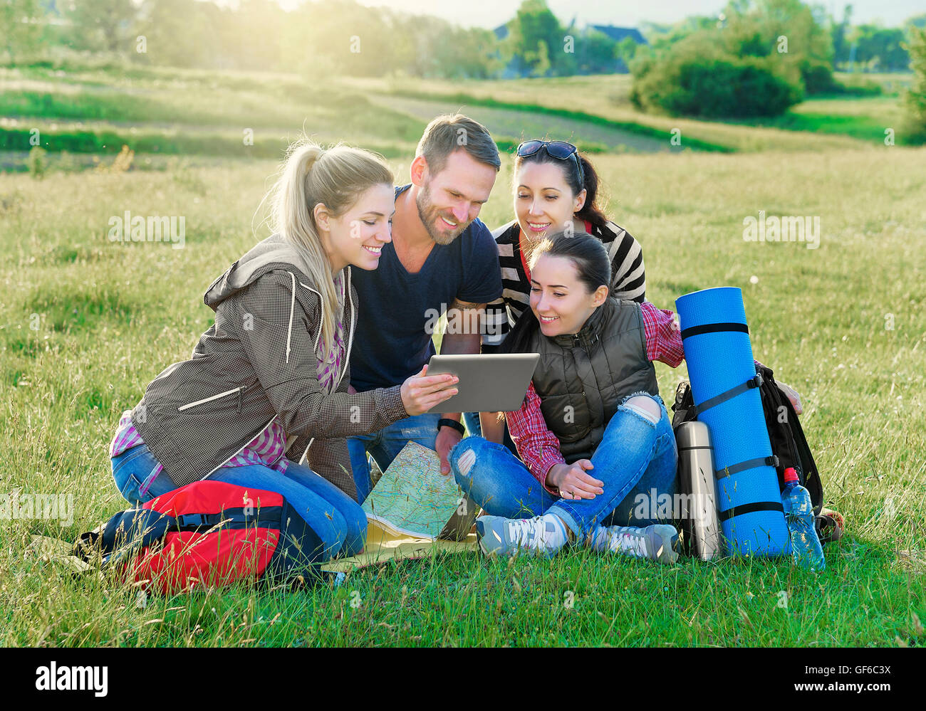 Group hikers on the grass with backpack used tablet pc, summer outdoor ...