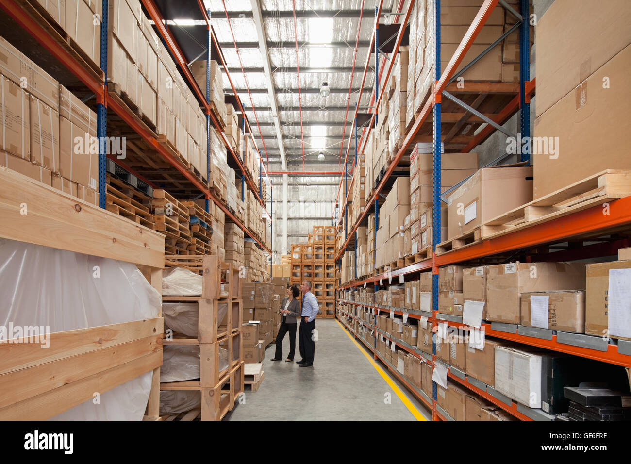 Two people standing in warehouse Stock Photo - Alamy