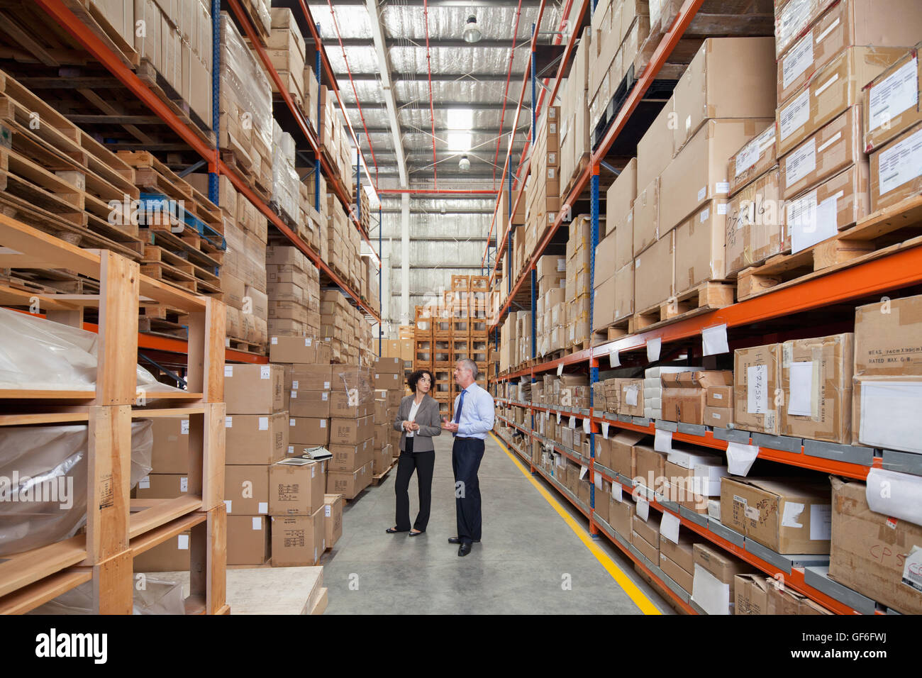 Two people standing in warehouse Stock Photo - Alamy