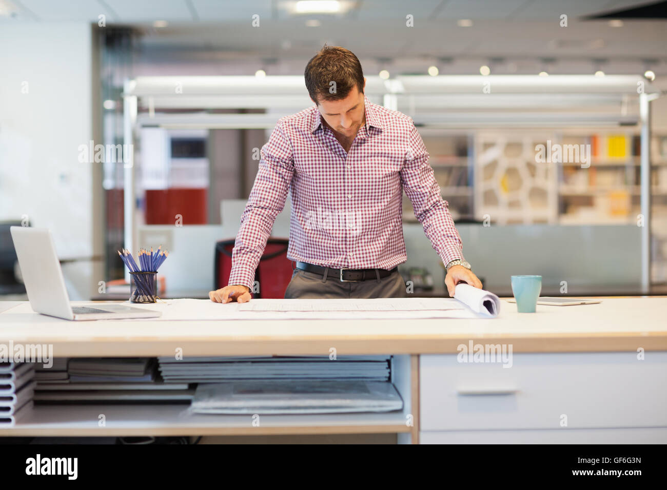 Businessman reviewing blueprint in office Stock Photo - Alamy