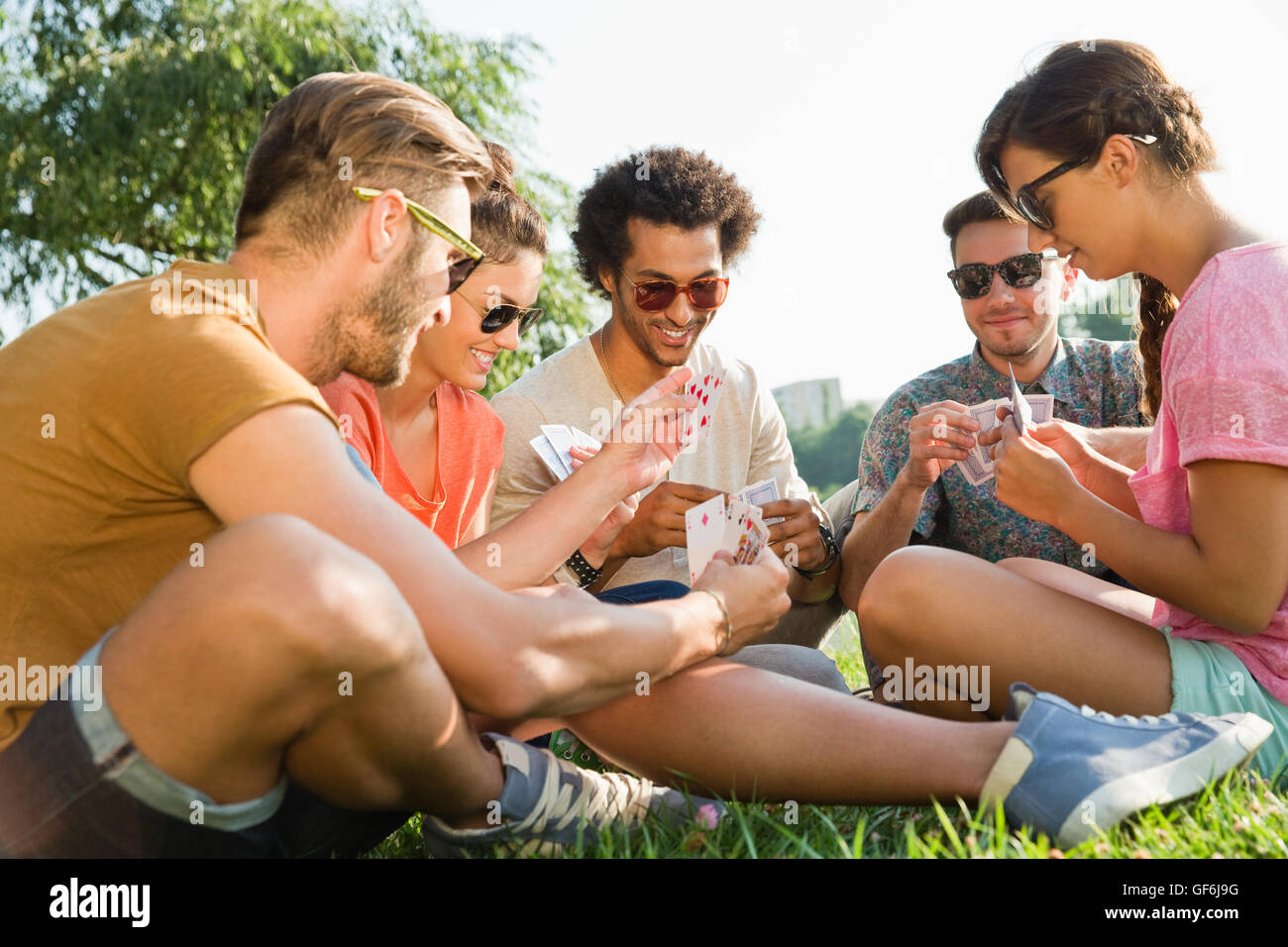 Friends playing cards and smiling Stock Photo - Alamy