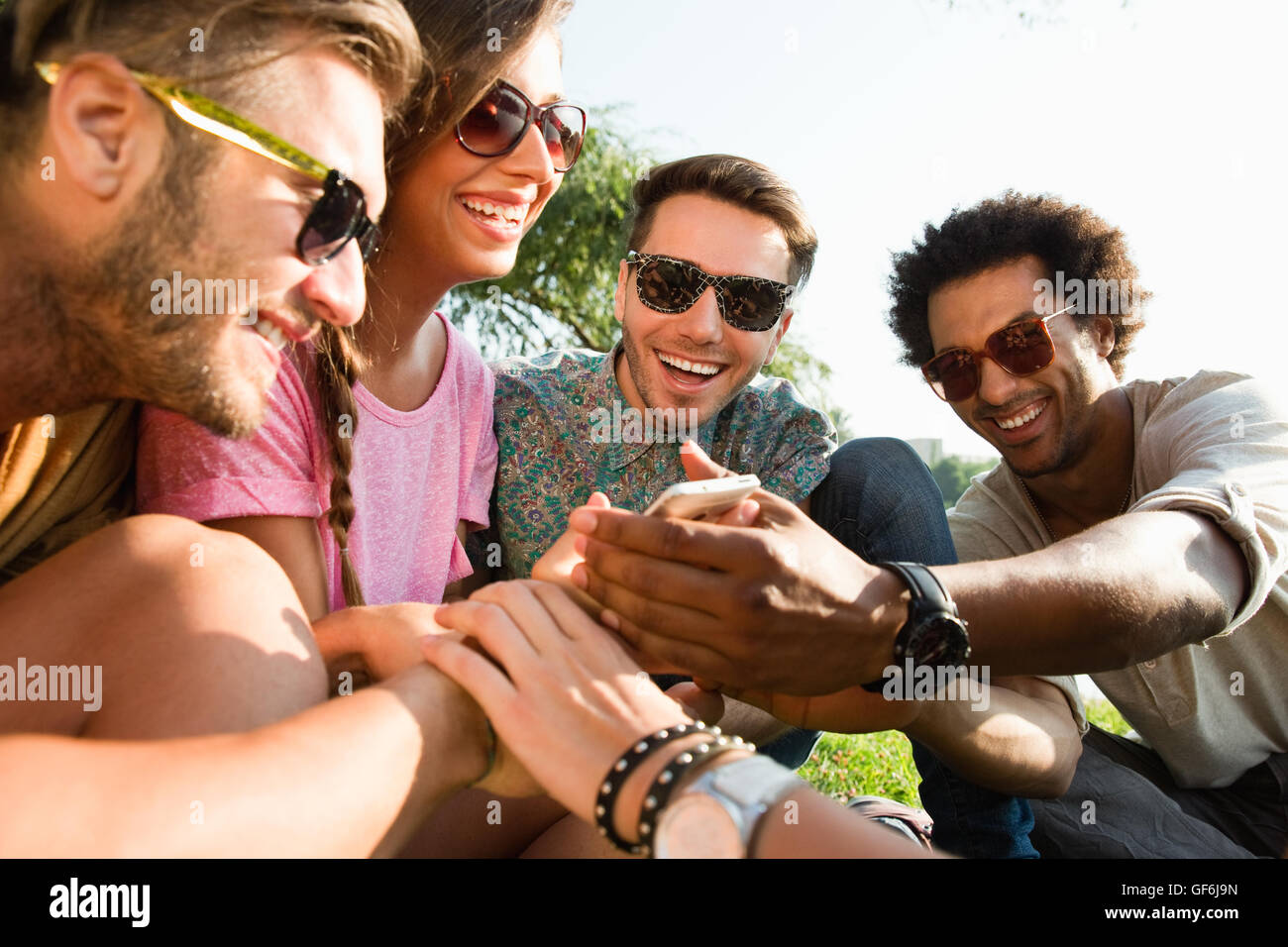 Friends using mobile phone and smiling Stock Photo - Alamy