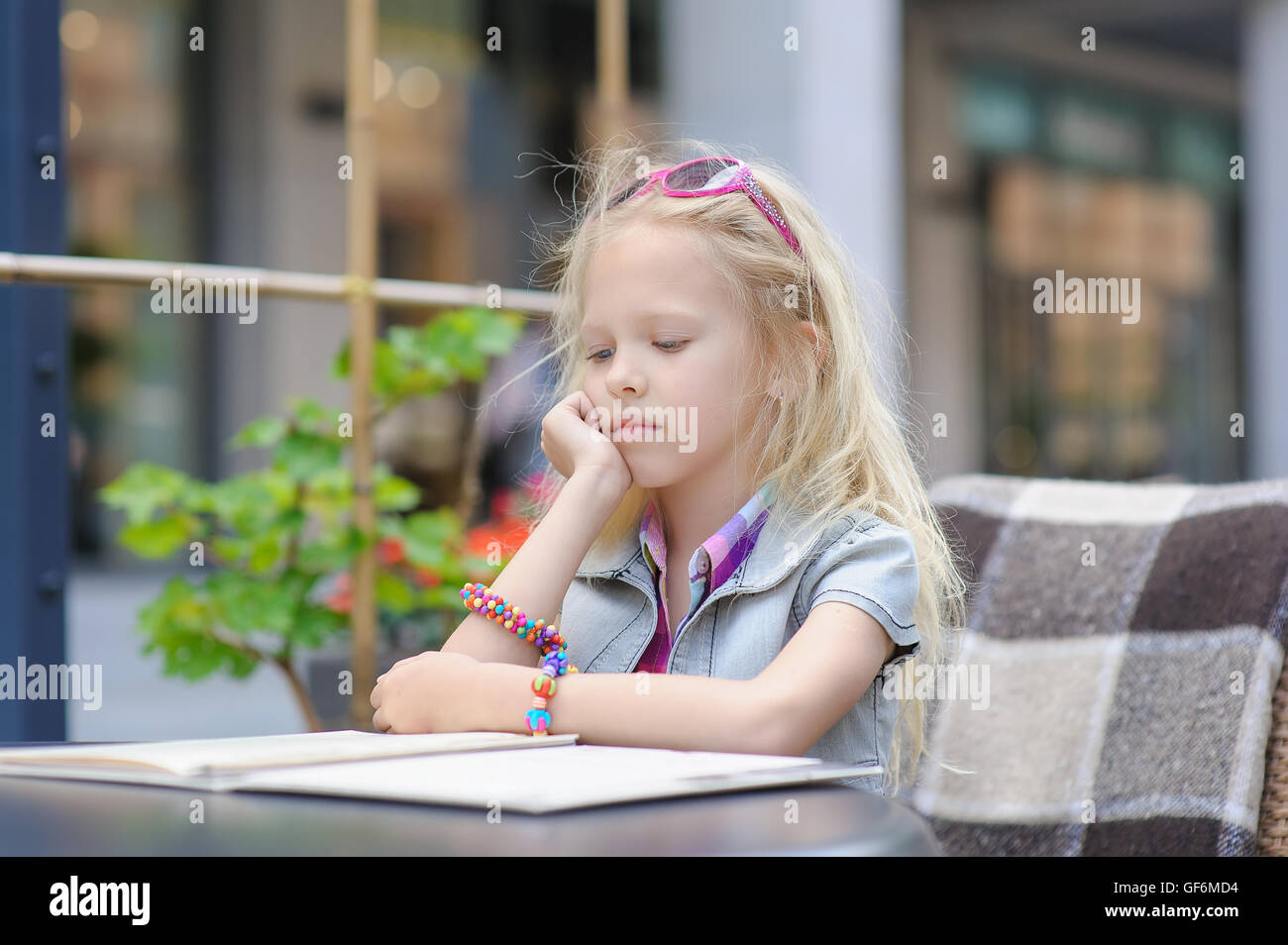 Adorable child reading menu in café. Toddler tired girl in beautiful ...