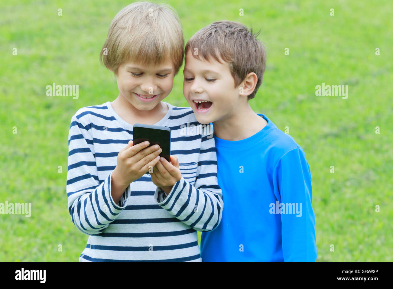 Boys with mobile phone. Children smiling, looking to screen, playing ...