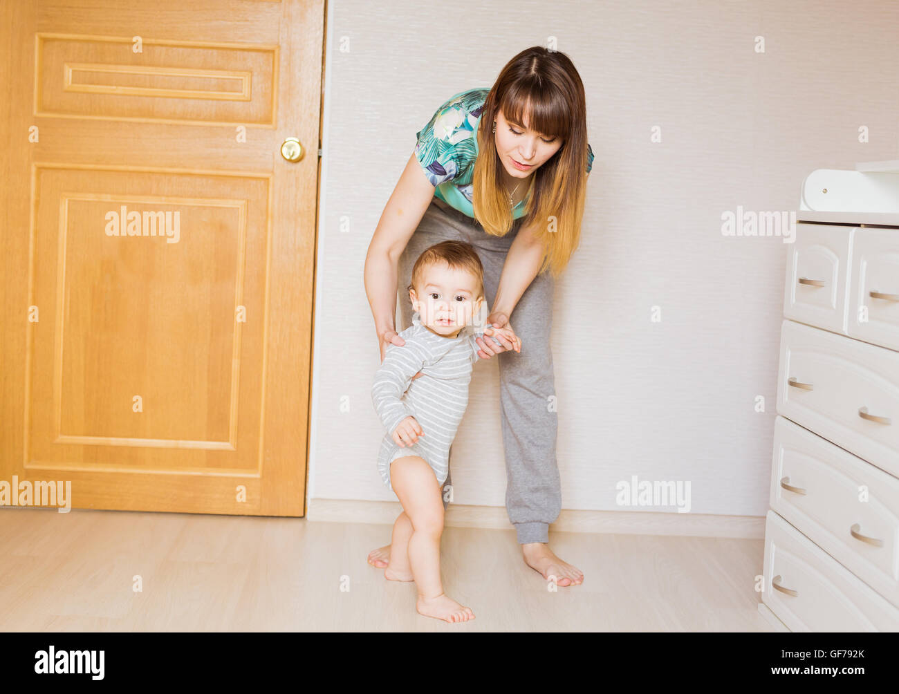 baby taking first steps with mother help Stock Photo - Alamy