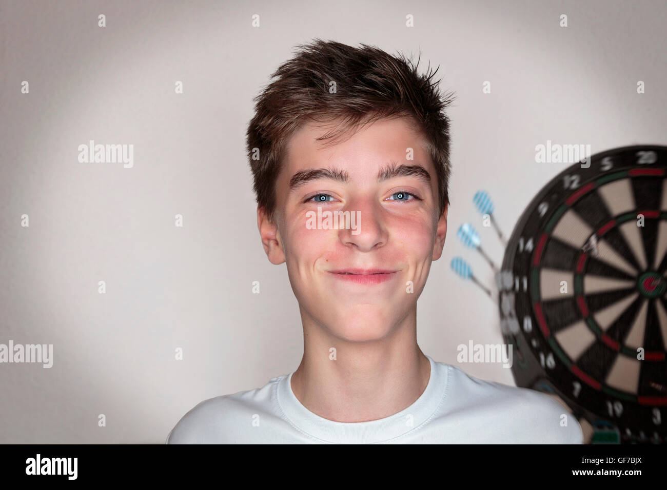 portrait of a teenage boy with dartboard in background Stock Photo - Alamy