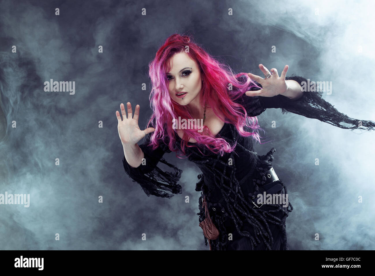 Halloween Witch creates magic. Attractive woman with red hair in ...