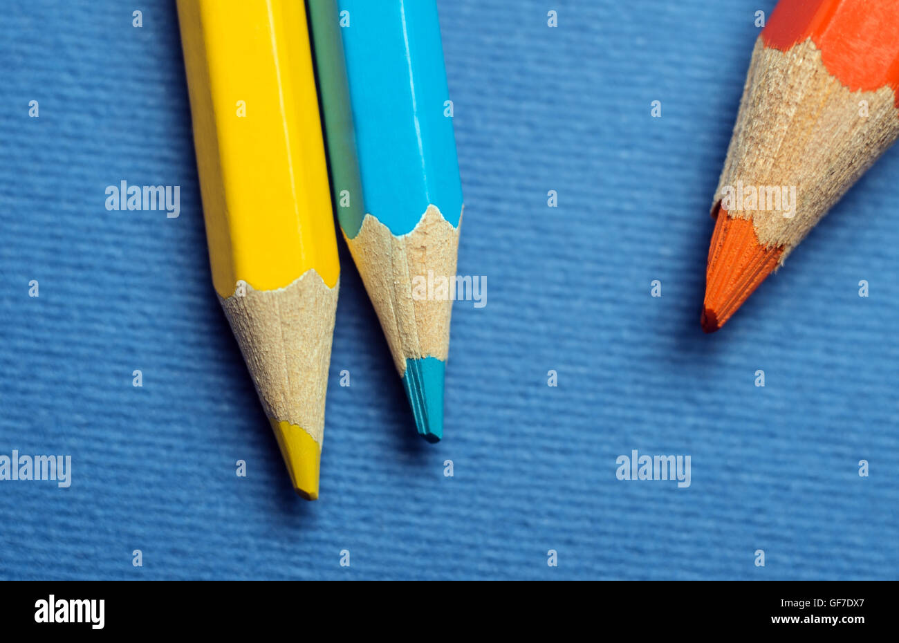 Three colored pencils on a blue list of paper Stock Photo - Alamy
