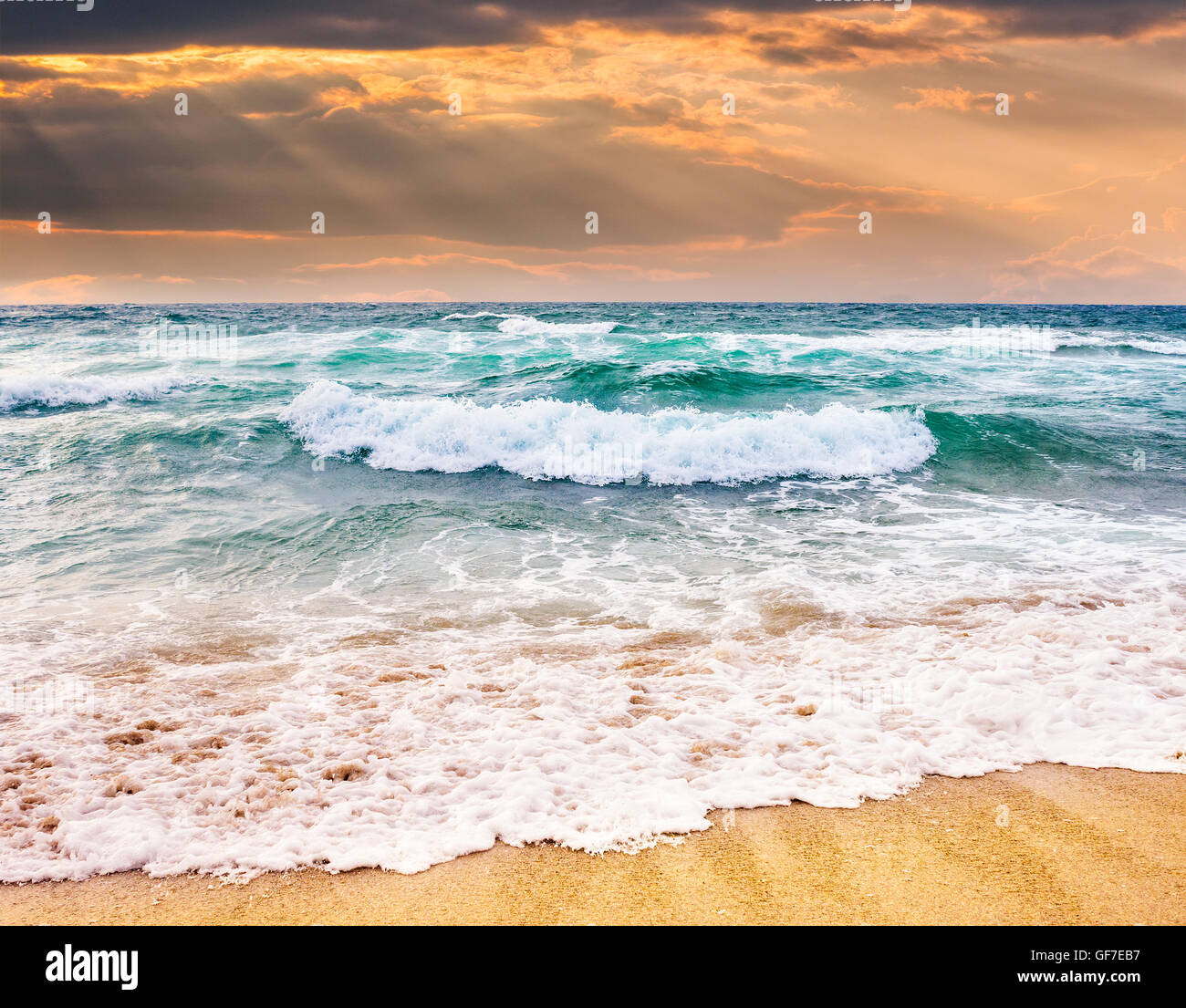 green and mighty sea wave attacks the sandy beach and break on them ...