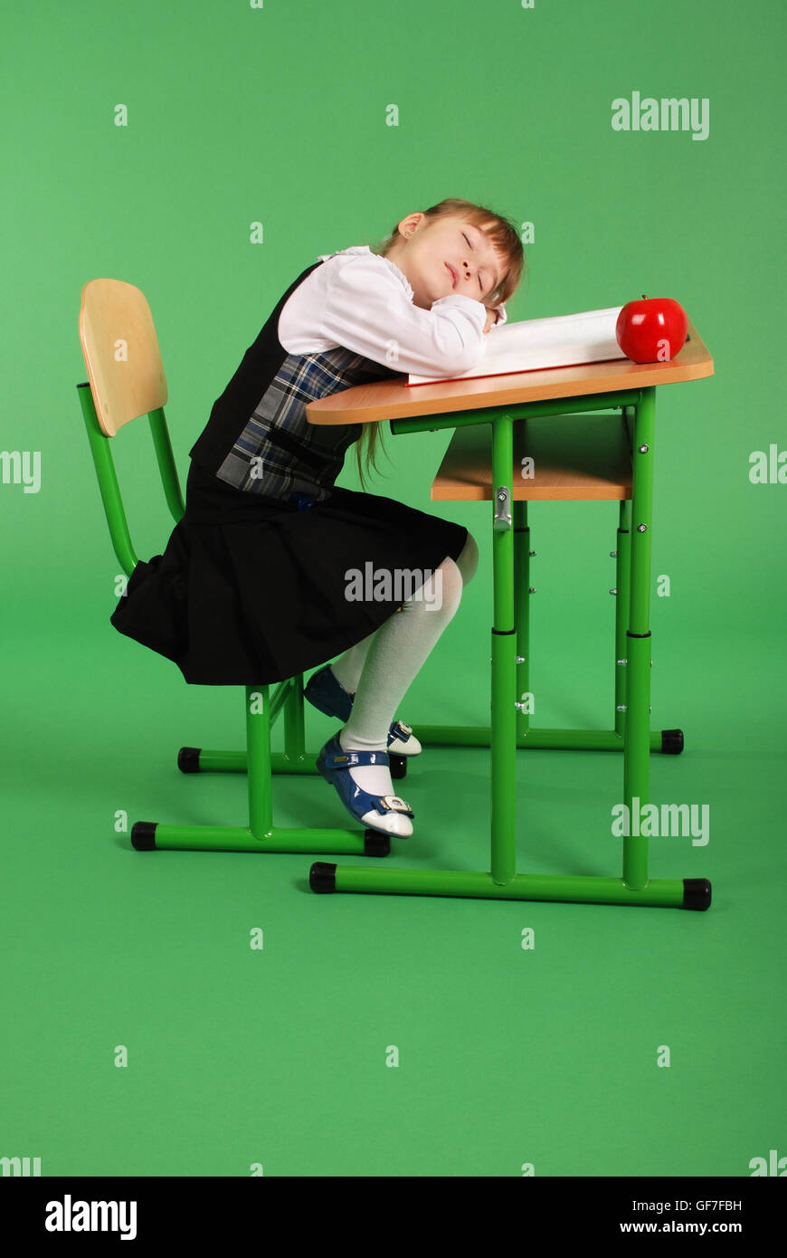 Girl in school uniform sleeping at his desk isolated on green ...
