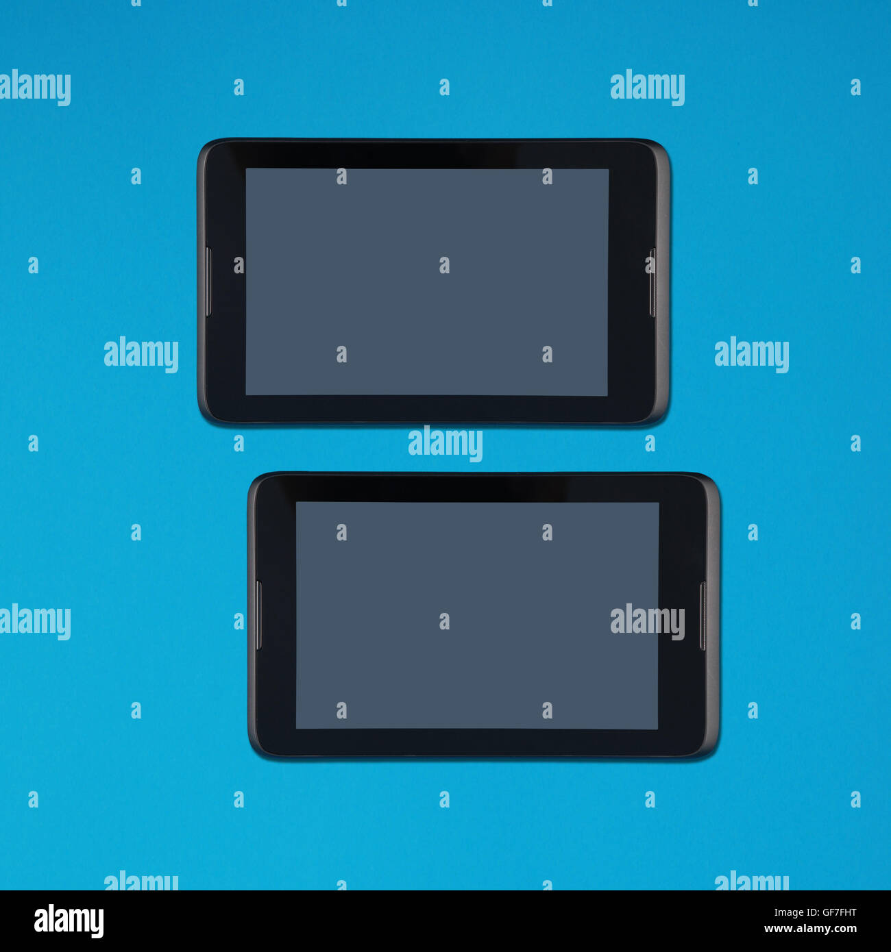 Tablet pc and smartphone lying side by side isolated on blue background ...