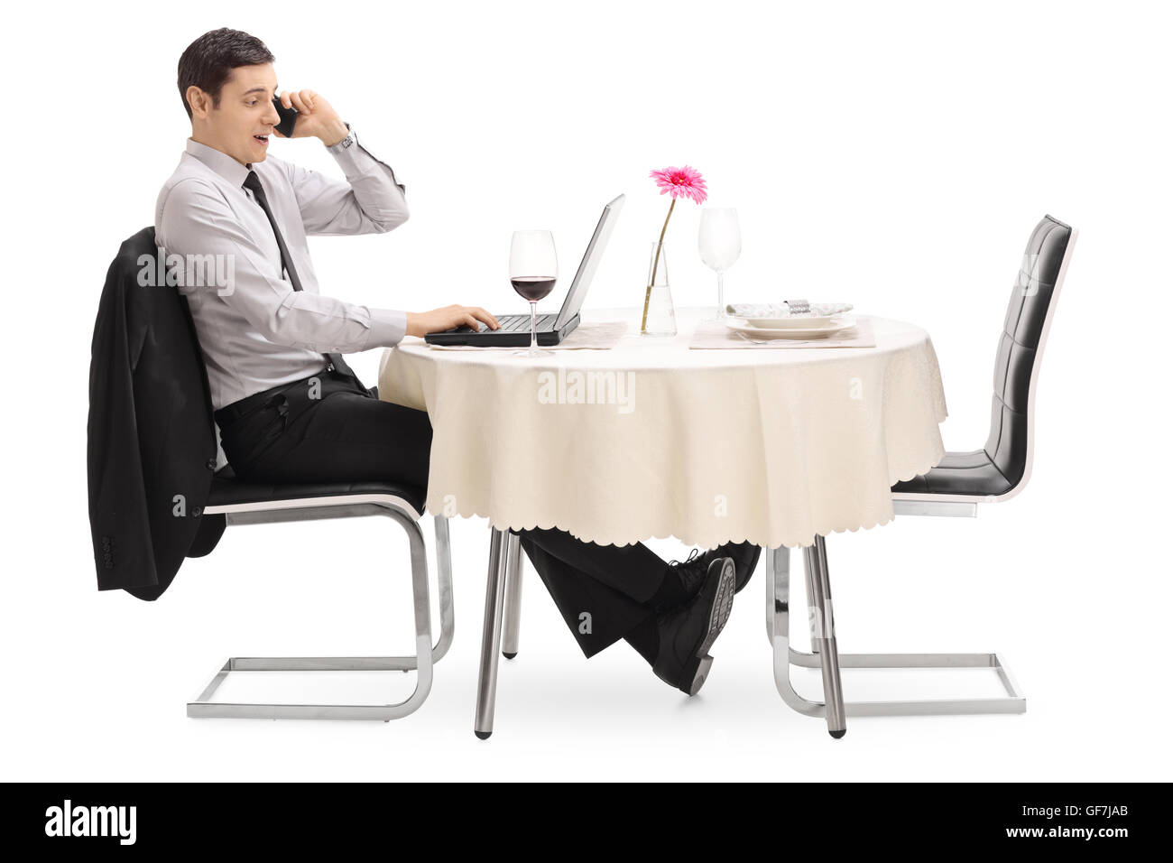 Young businessman talking on a cell phone and working on a laptop ...