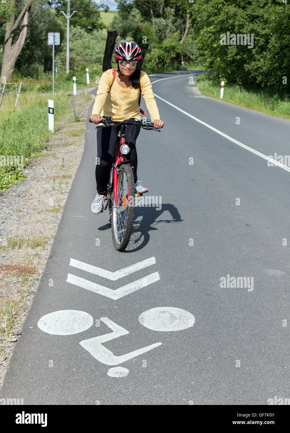 Young woman cyclist ride on bike at the road with signpost for ...