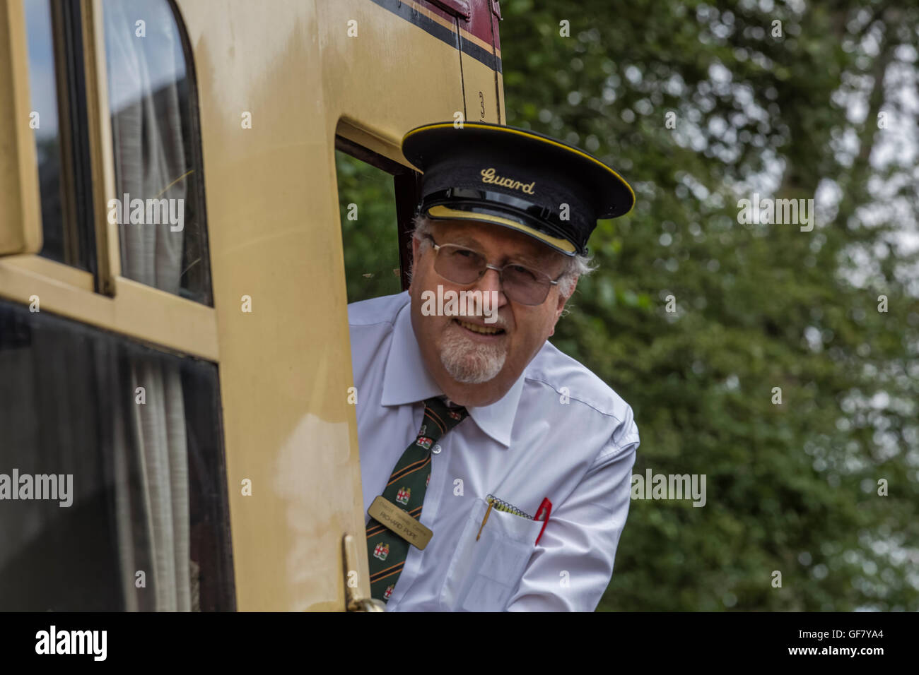Volunteer train guard dressed in authentic uniform sticks his head out ...