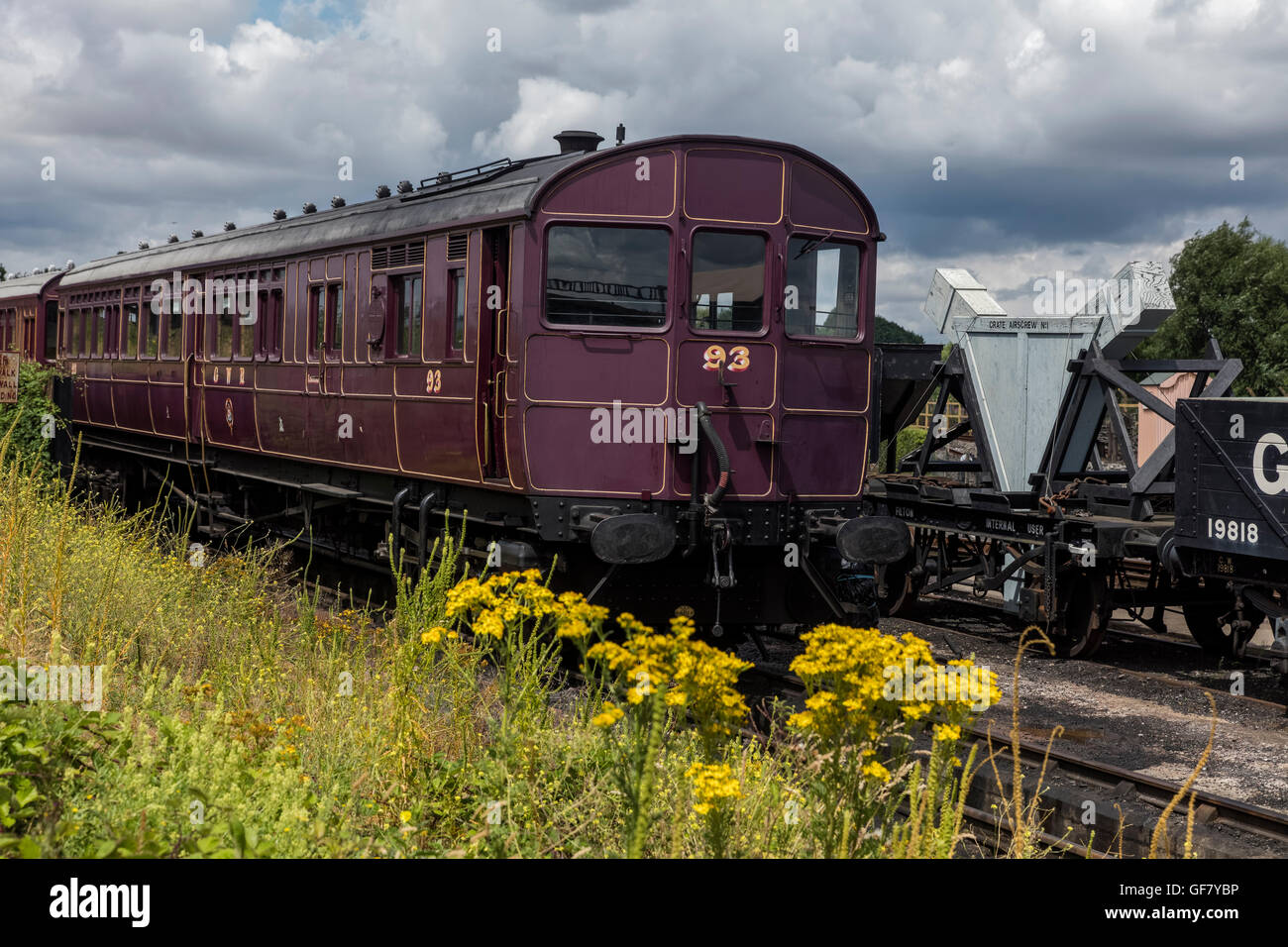 Old maroon painted train carriage with yellow wild flowers at the ...