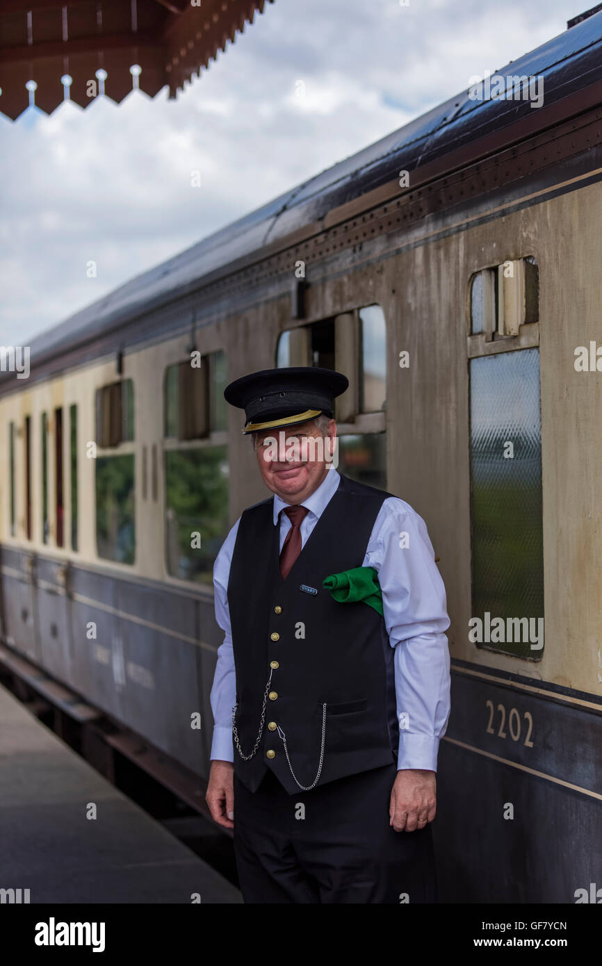 Train guard standing on the platform next to a train carriage painted ...