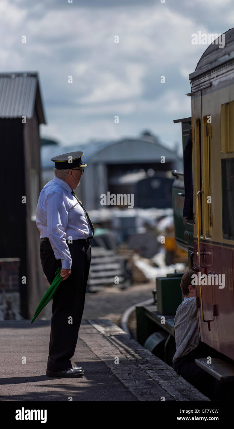 Guard on the platform next to a restored train carriage with a colleage ...