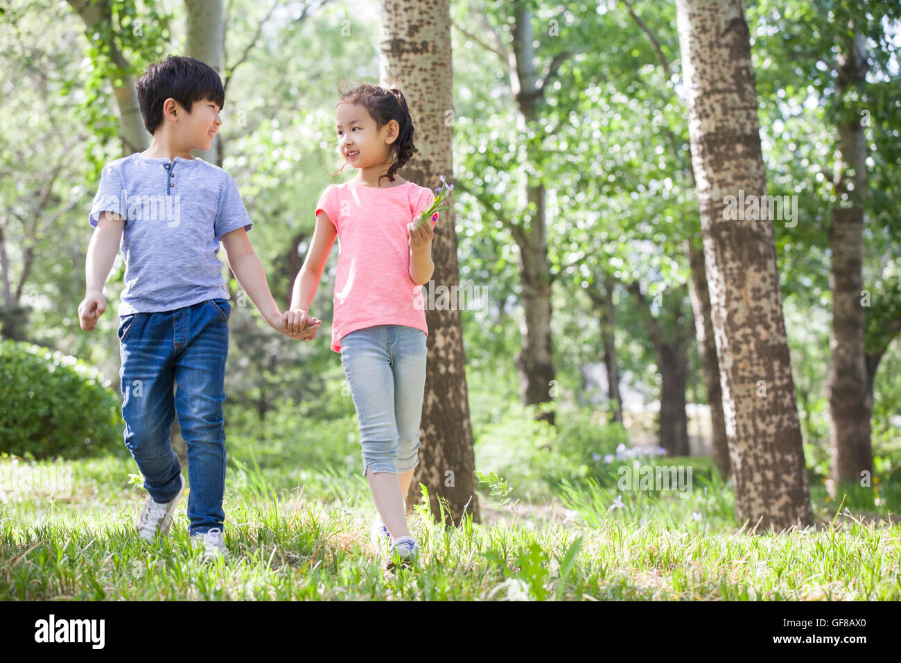 Happy Chinese children holding hands walking in woods Stock Photo - Alamy