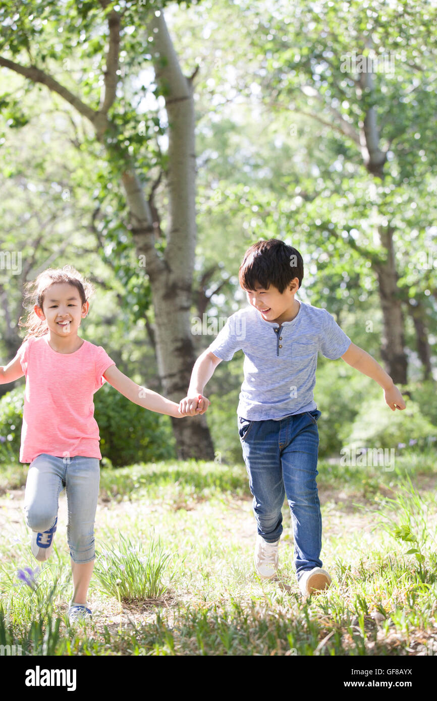 Happy Chinese children holding hands running in woods Stock Photo - Alamy