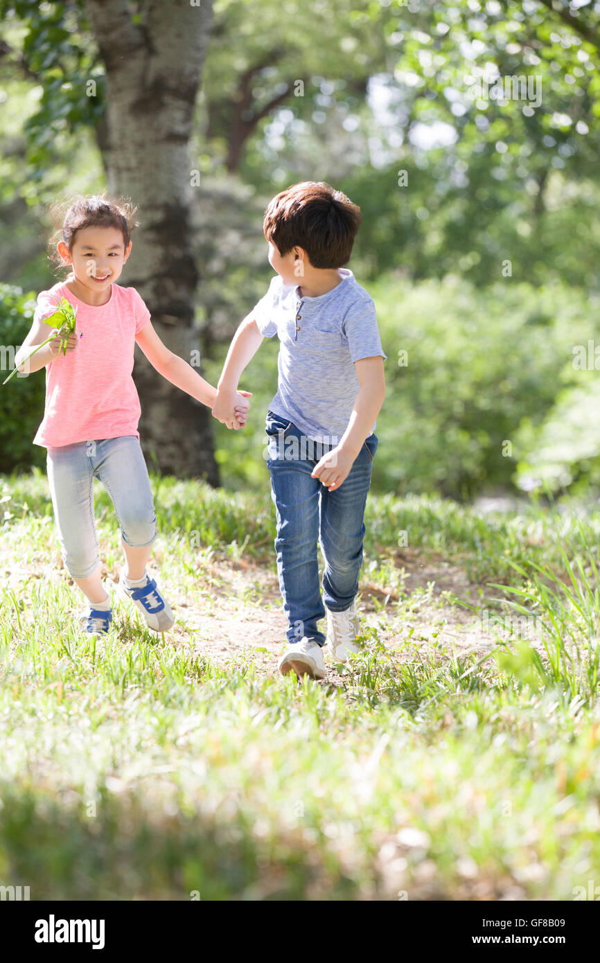 Happy Chinese children holding hands running in woods Stock Photo - Alamy
