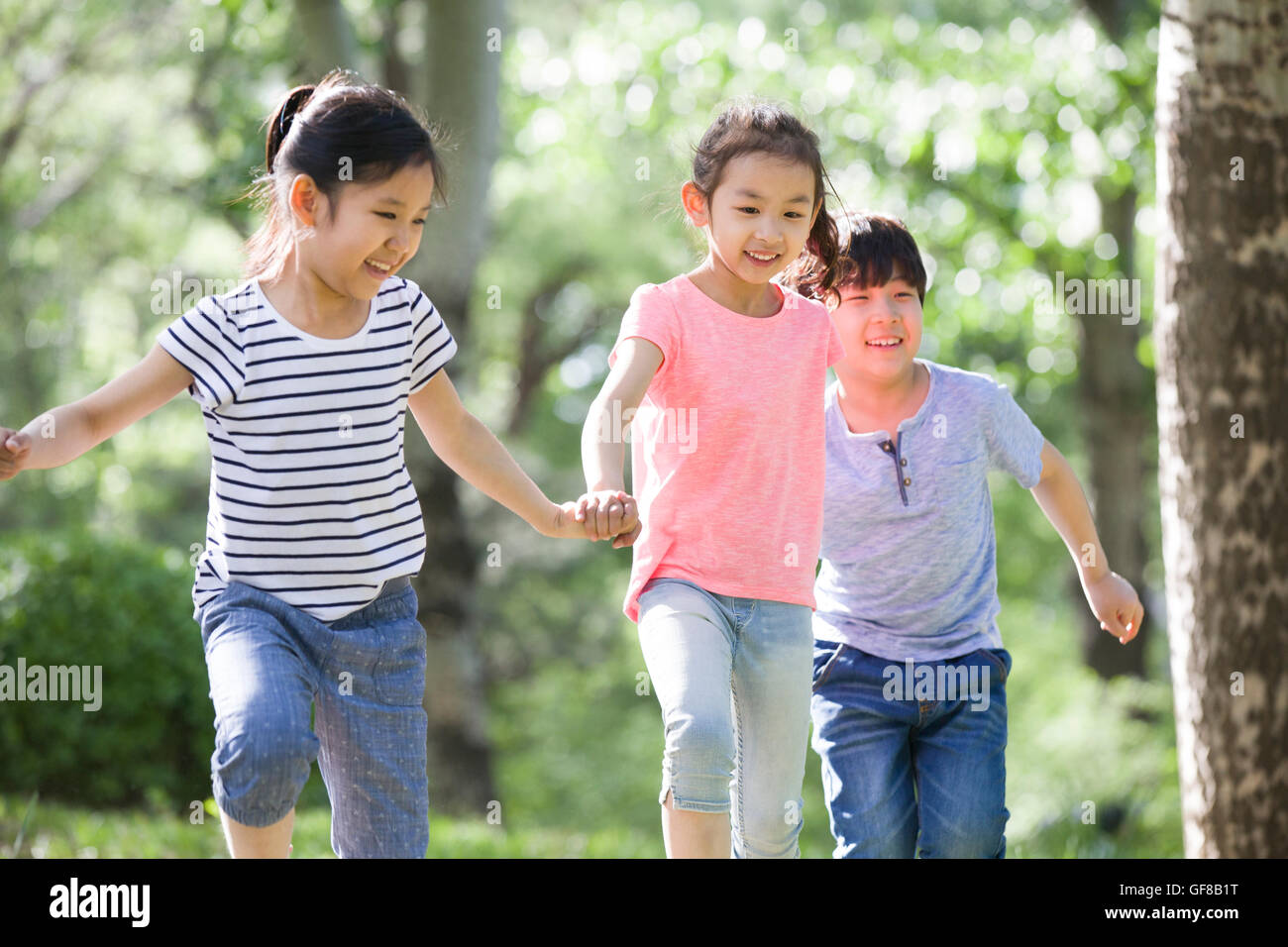 Happy Chinese children holding hands running in woods Stock Photo - Alamy