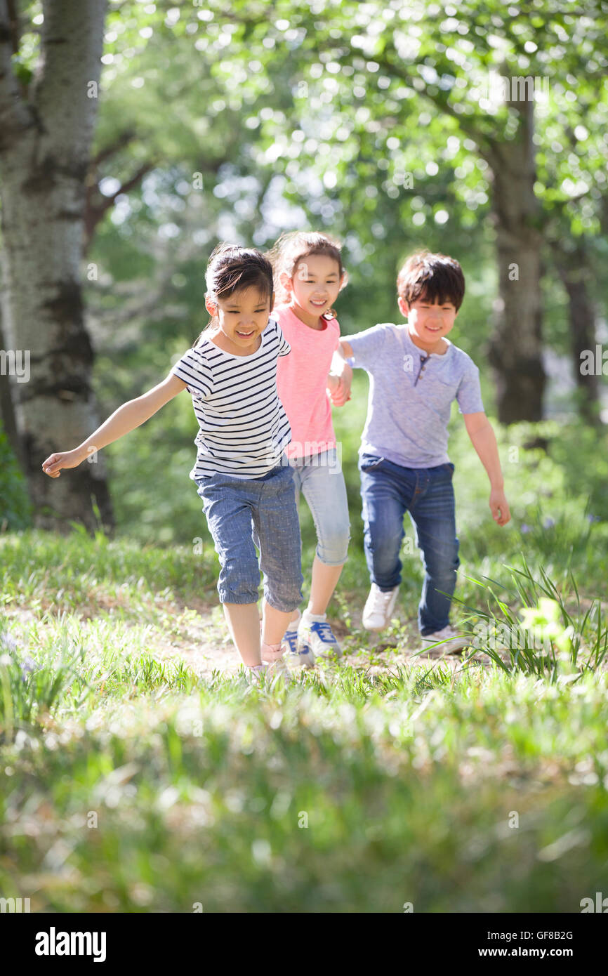 Happy Chinese children holding hands running in woods Stock Photo - Alamy