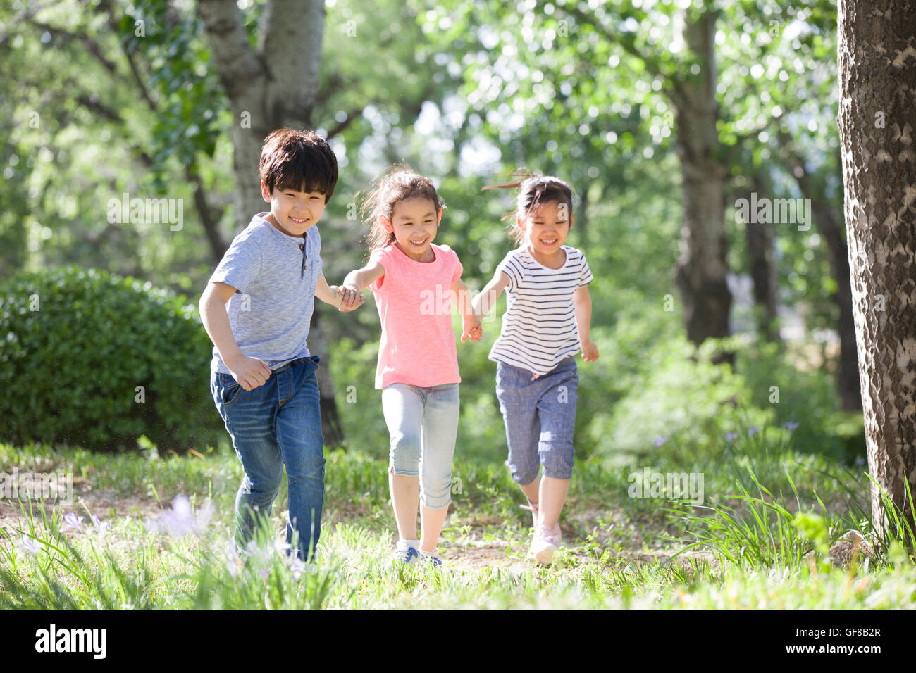 Happy Chinese children holding hands running in woods Stock Photo - Alamy