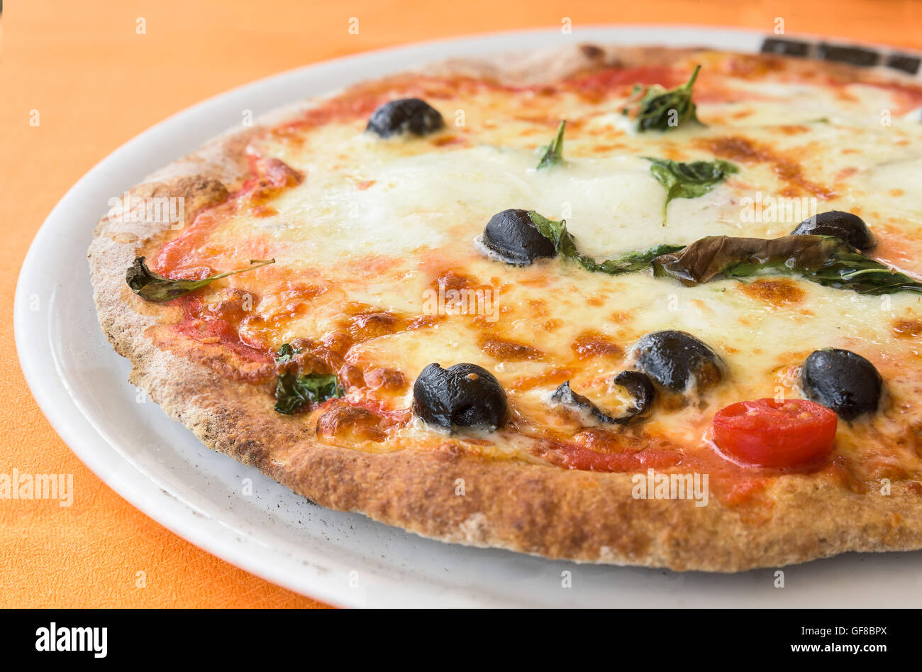 typical italian pizza with mozzarella, tomato cherry and olives on ...