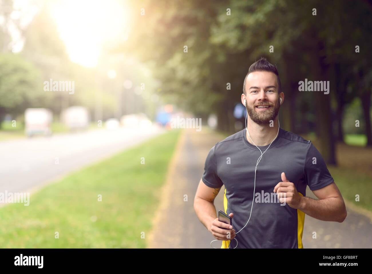 Man jogging along a tree lined sidewalk on a busy road approaching the ...