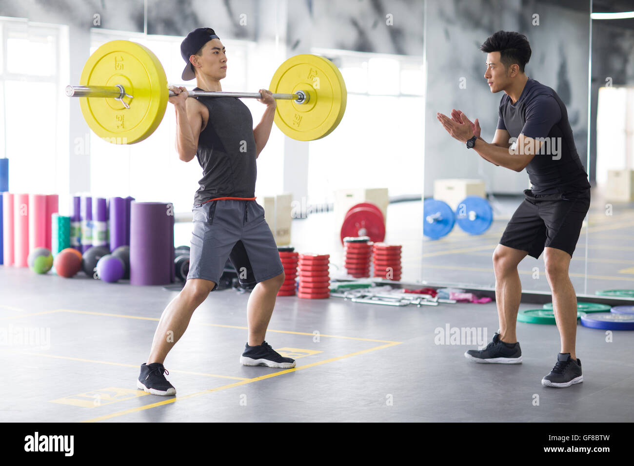 Young Chinese man working with trainer at gym Stock Photo - Alamy