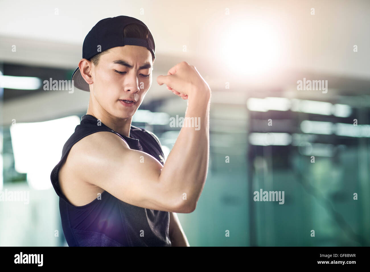 Young Chinese man in sports clothing flexing his muscles Stock Photo ...