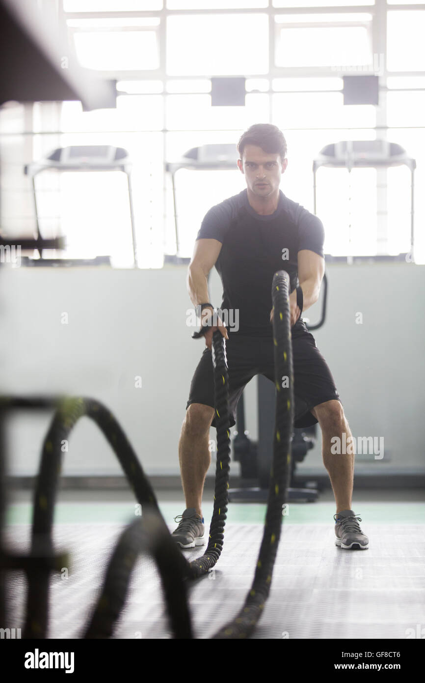 Young man exercising with battling rope at gym Stock Photo - Alamy