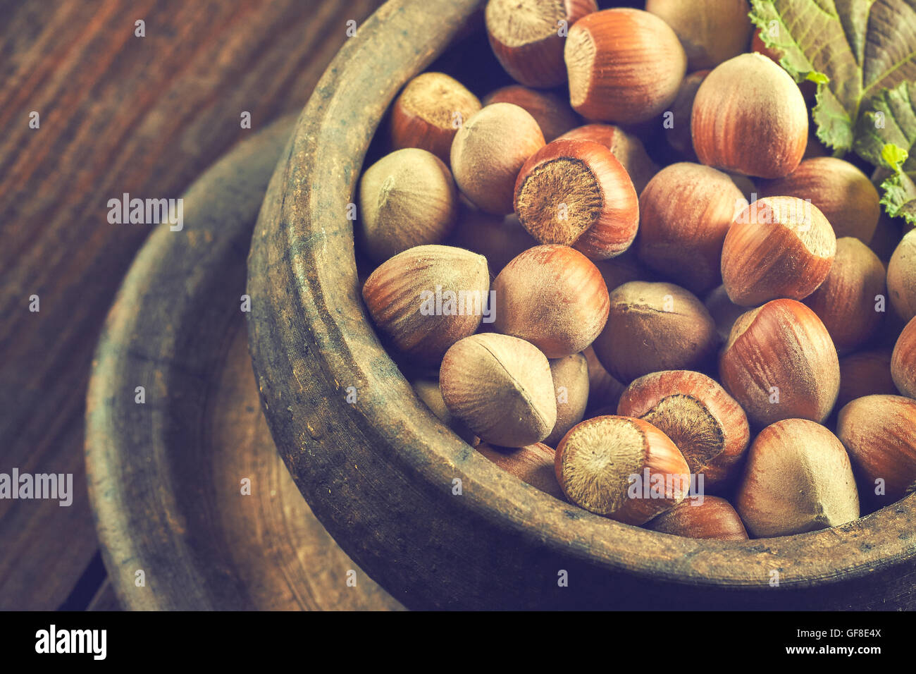 Hazelnuts in rustic round clay bowl on wooden background Stock Photo ...