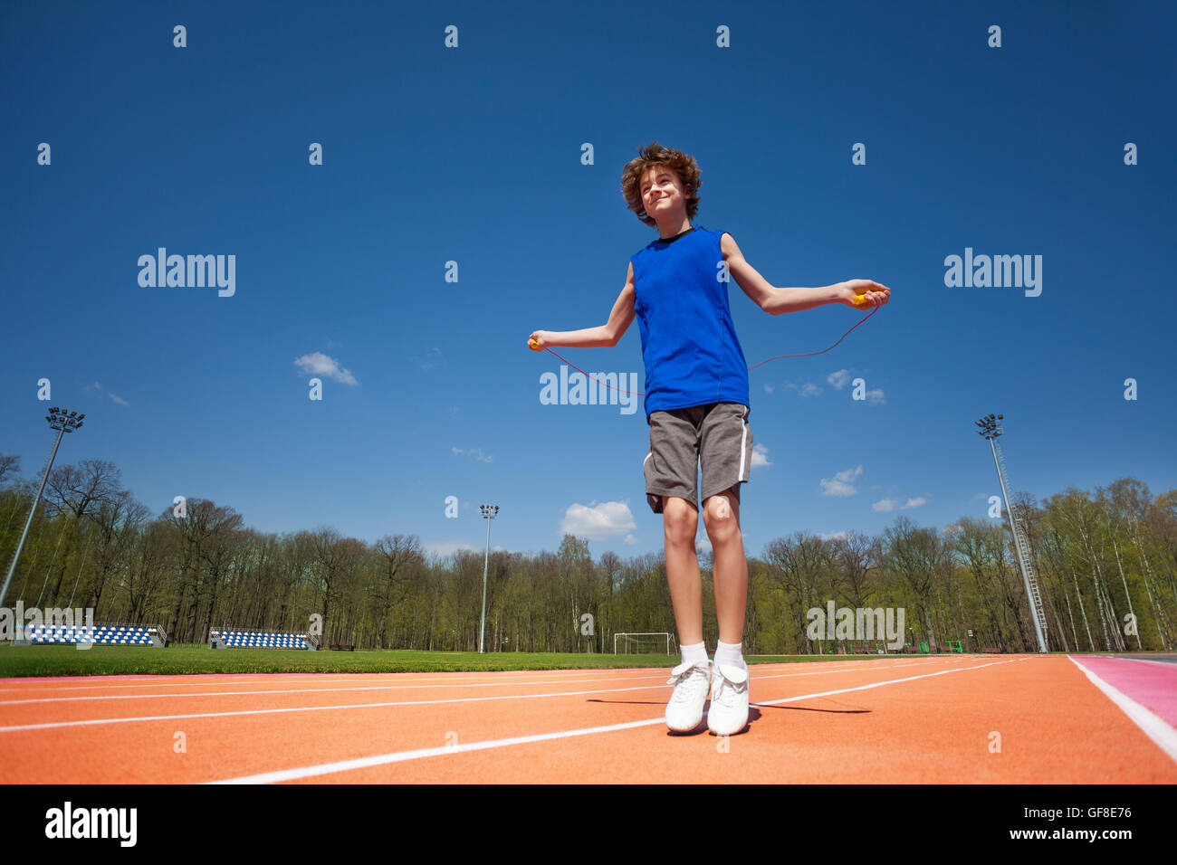 Smiling teenage boy jumping the rope outside Stock Photo - Alamy
