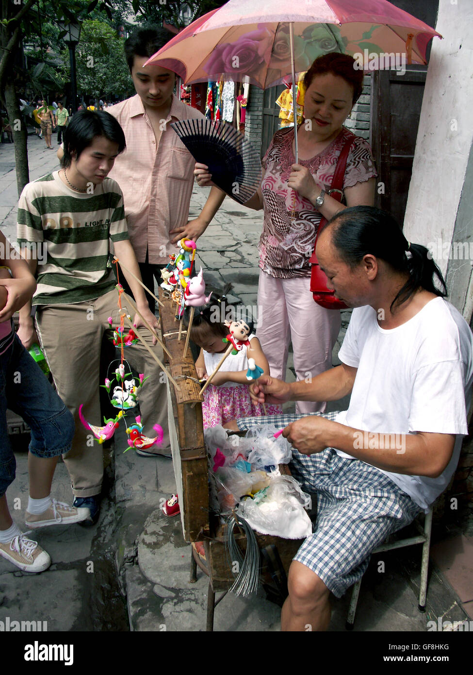 A traditional candy maker makes small figures in Ciqikou Ancient Town ...