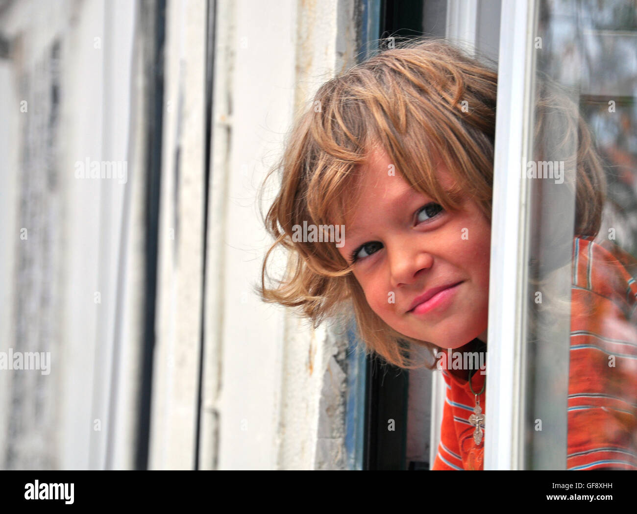 Smiling boy looking out of window Stock Photo - Alamy