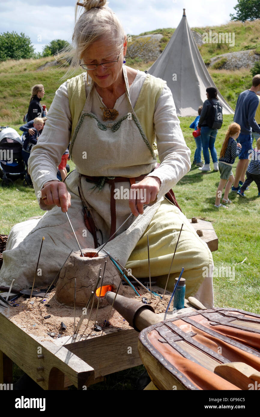 A woman shows the early medieval glass pearl production by help of ...