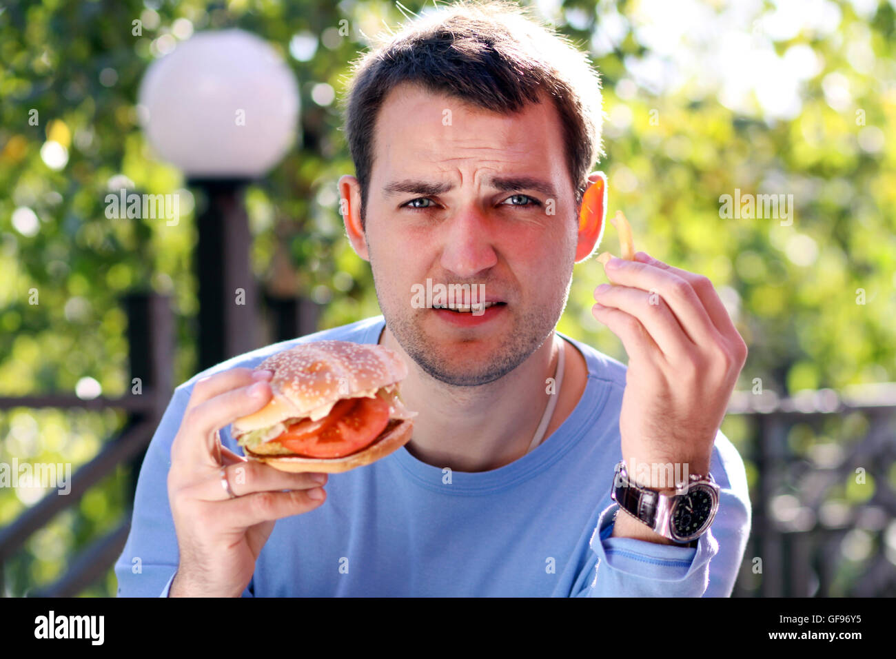 Young man eating burger in fast food Stock Photo - Alamy