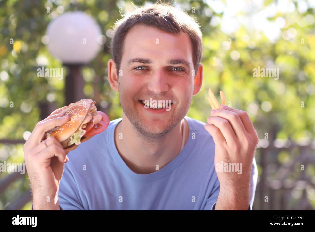 Young man eating burger in fast food Stock Photo - Alamy