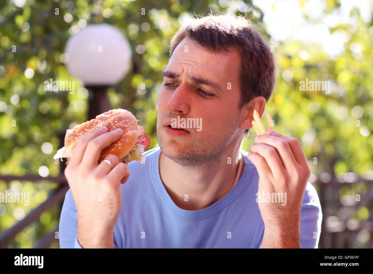Young man eating burger in fast food Stock Photo - Alamy