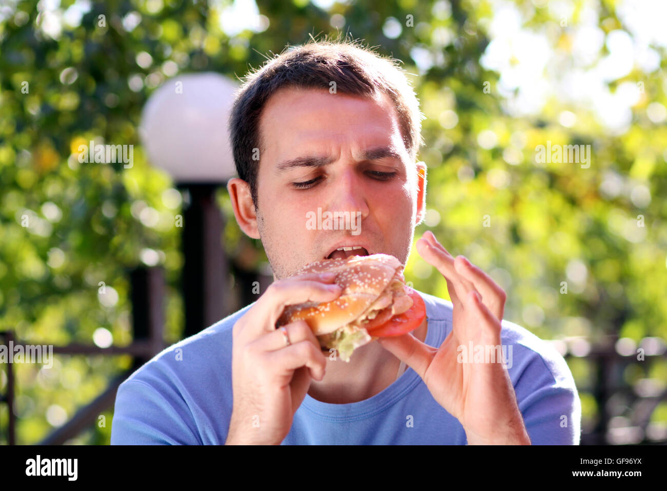 Young man eating burger in fast food Stock Photo - Alamy