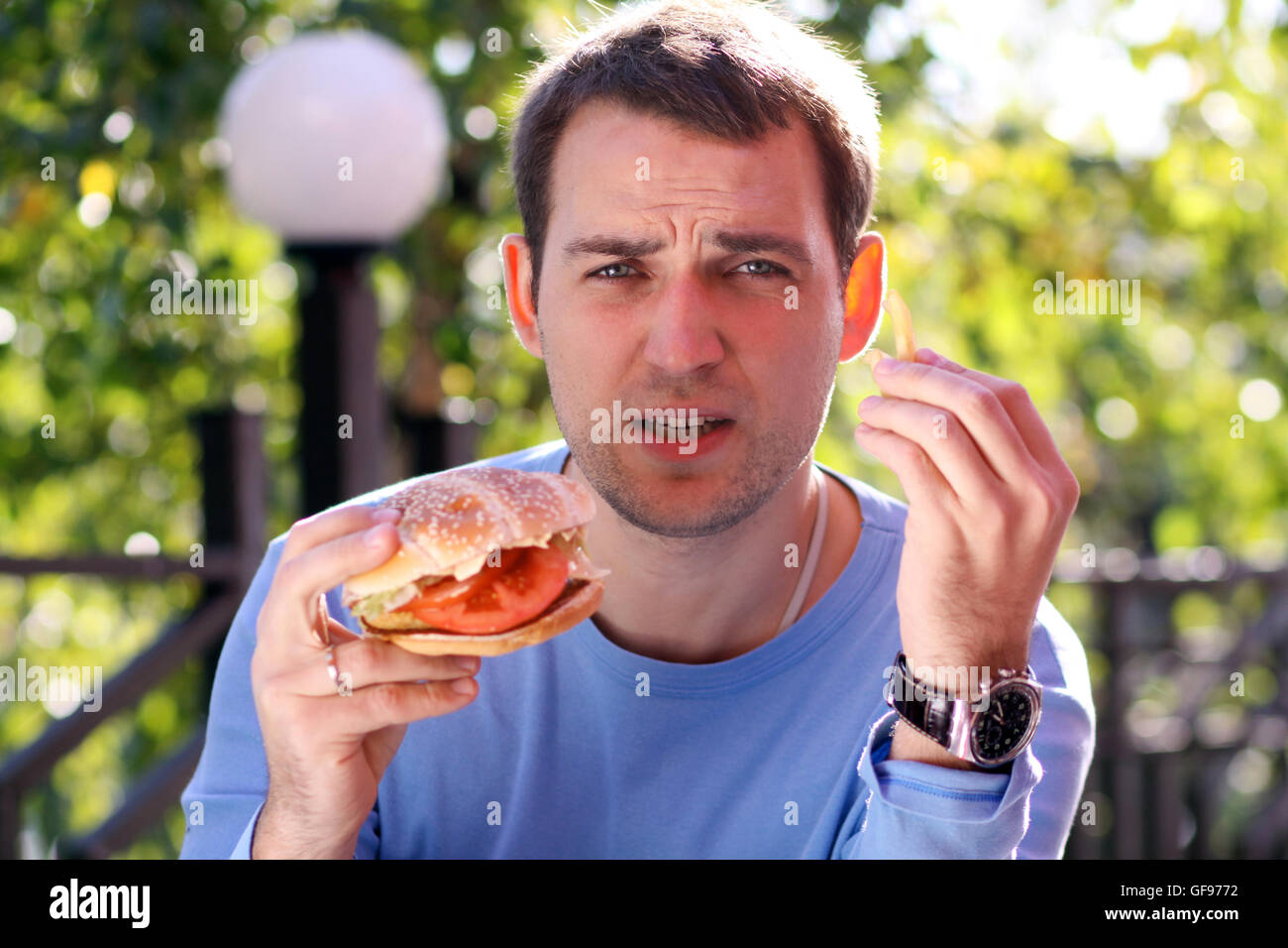 Young man eating burger in fast food Stock Photo - Alamy