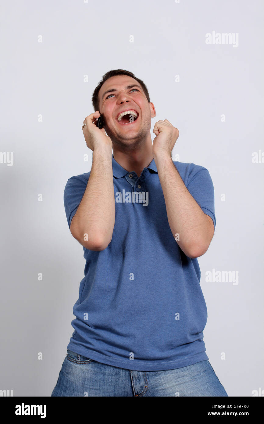 Smiling young man on his mobile phone against a white background Stock ...