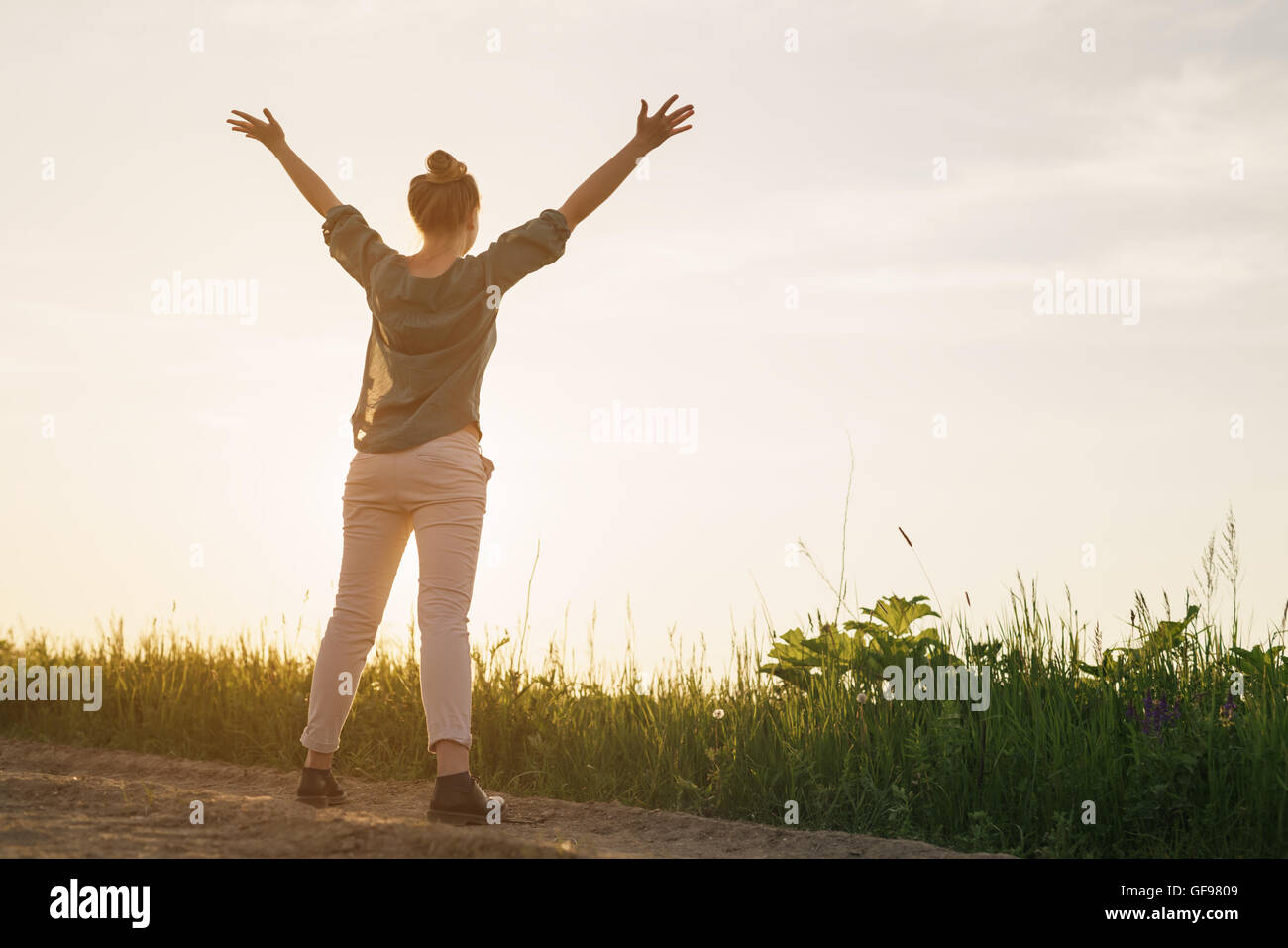 female teen girl stand feel freedom with arms stretched to the sky copy ...