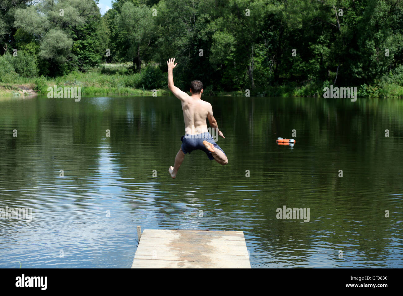 Young man jumping into lake Stock Photo - Alamy